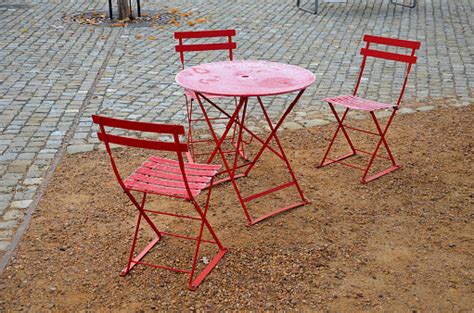 자갈이 깔린 광장의 카페에 빨간 의자와 둥근 테이블로 압축 된 자갈표면 모든 것은 매일 밤 접고 청소 할 수있는 가벼운 재료로 만들어집니다 얼음 장식 금속에 대한 스톡 사진
