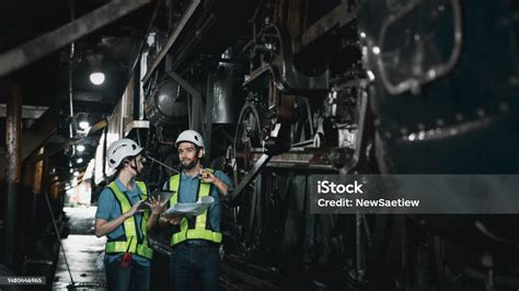 엔지니어가 공장에서 일하고 있습니다 기계의 준비 상태를 수리하고 검사하는 것을 돕는 작업자 기계 기술자가 오작동하는 열차 차고에서 엔진을 유지 관리하고 있습니다 2명에 대한
