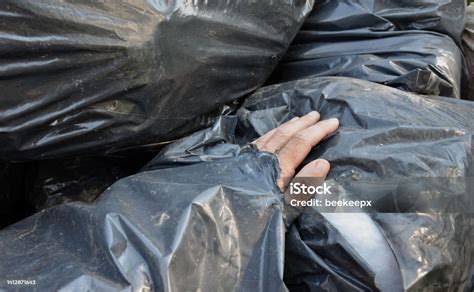 검은 플라스틱 쓰레기 봉투에 죽은 남자 사람의 손이 엿보는 죽은 자를 위한 가방 공공 폐기물 덤프 현장 범죄 경찰 조사 납치 몸통 훼손 살해 경찰관에 대한 스톡 사진 및