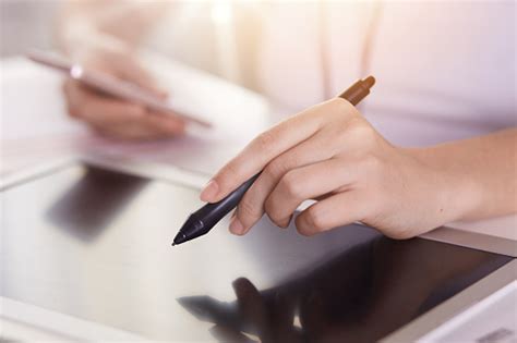 디지털 태블릿 Pc에서 스타일러스로 작업하는 여성의 얼굴없는 초상화를 닫고 다른 손에 스마트 폰을 들고있는 여성 무선 인터넷을 사용하여 집에서 온라인 작업을하는 여성 단일