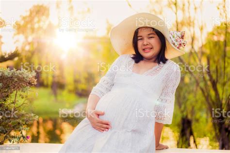 임산부는 아이를 돌보면서 정원에서 새로운 삶에 행복을 느낍니다 임신 한 배에 아기를 들고 젊은 기대 어머니 출산 전 관리 및