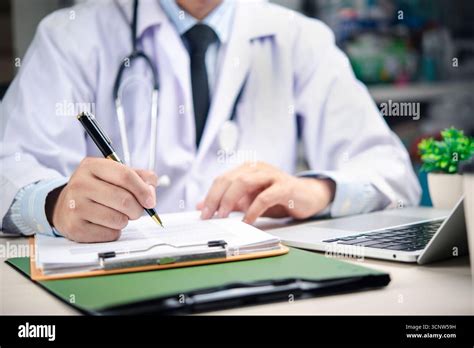 Doctor Writing On Medical Documents With A Pen Reviewing Patient