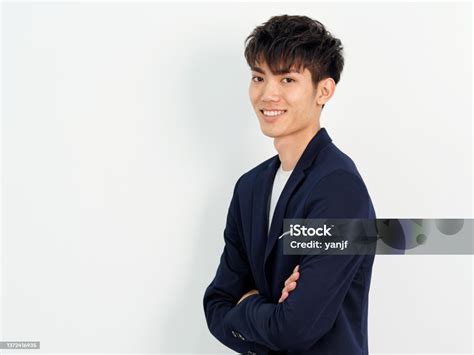 진한 파란색 레저 슈트를 입은 잘생긴 중국 청년의 초상화가 흰색 벽 배경에 서서 포즈를 취하고 있습니다 미소를 지으며 자신 있게 카메라를 바라보며 전면보기를 볼 수 있습니다