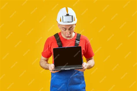 Premium Photo Surprised Male Engineer In Helmet Holds Laptop With