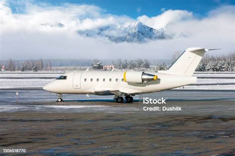 맑은 화창한 날에 높은 경치가 좋은 산의 배경에 겨울 공항 앞치마에 흰색 럭셔리 비즈니스 제트 0명에 대한 스톡 사진 및 기타 이미지 Istock