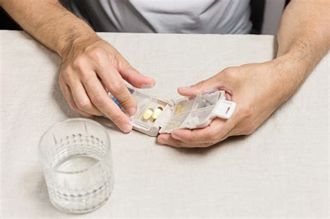 중년의 남자는 손에 비타민과 의약품을 매일 섭취하기 위해 열린 알약 상자를 들고 약을 마신다 인간의 건강 개념 매일 복용 의학 아름다움과 건강을위한 라이프 스타일 자기 관리