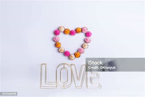 하트 모양으로 배열 된 여러 가지 빛깔의 크림 충전과 모든 종류의 초콜릿 과자의 상단보기 축제 구성고립 흰색 배경에 와이어 단어 사랑 해피 발렌타인 데이 공간을 복사합니다