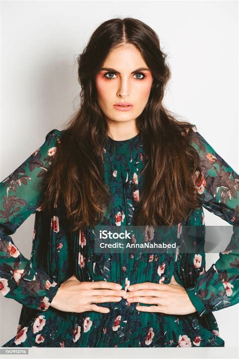 긴 어두운 머리를 가진 아름 다운 여자의 스튜디오 샷 밝은 분홍색 메이크업 녹색 드레스를 입고 허리에 손을 유지 눈 신체 부분에