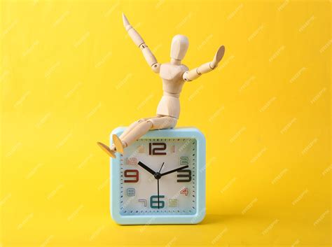 Premium Photo Wooden Puppet And Alarm Clock On Yellow Background