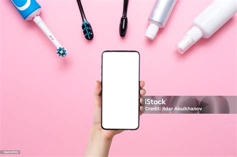 분홍색 배경에 스마트 폰과 다양한 칫솔 치약 및 입 청정기와 손을 잡습니다 모의 현대 치과의 개념 전기 칫솔에 대한 스톡 사진 및 기타 이미지 Istock
