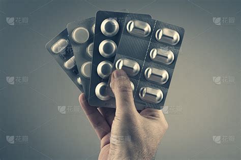 白人男性的手拿着许多药丸包装箔的特写