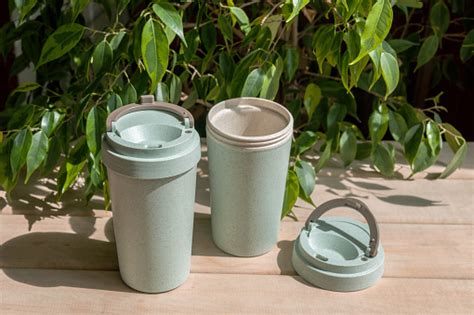 녹색 단풍의 배경에 나무 책상에 커피 차 및 기타 뜨겁고 차가운 음료를위한 플라스틱 재사용 가능한 열성 컵 레이블의 공간을 복사합니다 0명에 대한 스톡 사진 및 기타 이미지