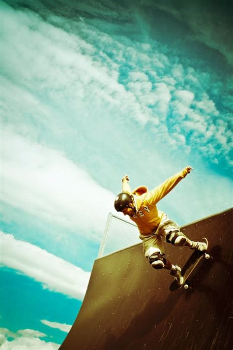 검은 헬멧 경사로 공중 구름 낀 하늘 균형 기술 노란 블라우스 다이나믹한 도시의 라이프스타일 레저 레크리에이션 모험 무릎 패드 민첩한 보호 장구