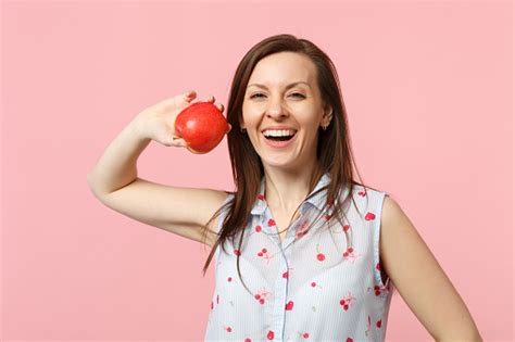 분홍색 파스텔 벽 배경 스튜디오 초상화에 고립 된 신선한 잘 익은 빨간 사과 과일을 들고 여름 옷에 젊은 여자를 웃 고 사람들은 생생한 라이프 스타일 휴식 휴가 개념입니다