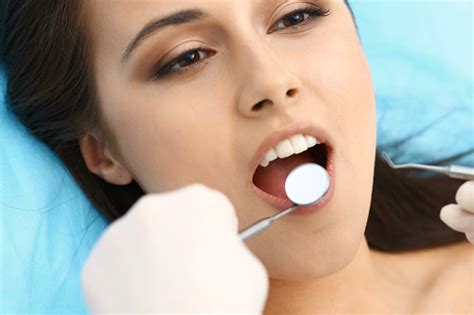 젊은 여성 환자는 치과 의사 사무실 방문 건강 바로 화이트 치아 치아에서 일 하는 의사는 동안 구강 검 진 기간 동안 오픈 입으로 치과 자에 앉아 아름 다운 여자 치과 구강