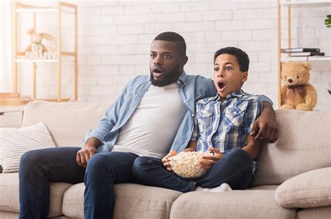 감정적 인 흑인 아버지와 유치원 딸이 집에서 함께 액션 영화를보고 팝콘을 먹고 여유 공간을 2명에 대한 스톡 사진 및 기타 이미지 Istock