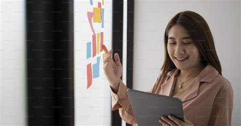 웃고 있는 사업가는 유리 벽에 스티커 메모를 읽고 디지털 태블릿을 사용합니다 사진 Unsplash의 그것의 게시 이미지