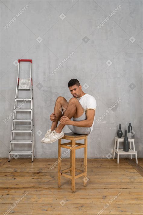 무릎을 구부린 채 의자에 앉아 있는 남자 사진