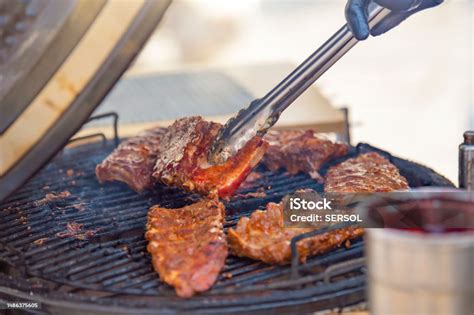 갈비를 굽는 과정 한 남자가 고기를 굽는 동안 집게로 구운 갈비 조각을 돌립니다 바비큐와 야외 요리의 계절입니다 0명에 대한 스톡 사진 및 기타 이미지 Istock