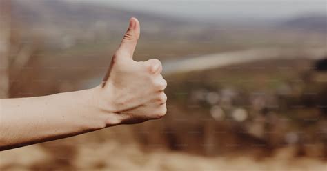 햇볕이 잘 드는 산의 배경에 엄지손가락을 치켜든 것처럼 보여주는 여자 손 승인 및 여행 개념 사진 Unsplash의 페이지 이미지