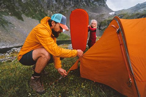 아이는 아버지를 도와 텐트를 치고 산에서 캠핑 장비를 갖추고 가족 여행 휴가 아빠와 딸 하이킹 여행 활동적인 모험 야외 활동 건강한 라이프 스타일 부모와 자녀 생태 관광