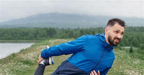 여름에 야외에서 운동하는 중년 스포츠맨 우울한 날 경치가 좋은 도로에 서서 워밍업 스트레칭 파란색 재킷을 입고 수염이 있습니다 사진 Unsplash의 자연 이미지