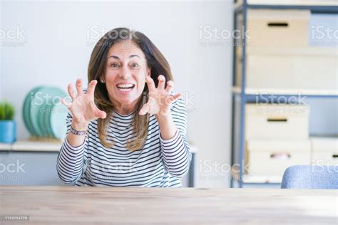 고양이 공격적이고 섹시한 표정으로 발톱 제스처를하고 재미 웃고 집에서 테이블에 앉아 중년 노인 여성 갈고리 발톱에 대한 스톡 사진 및 기타 이미지 Istock