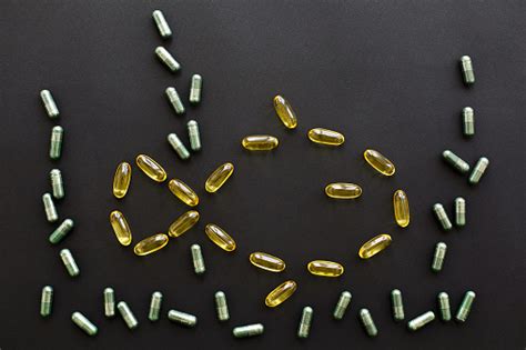 식이 보조 제 오메가 3 물고기 모양과 스피룰리나 알 약에 캡슐 조류 해 조류 어두운 배경에 플랫 레이 건강 지원 및 치료