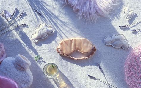 건강한 밤 수면 창조적 인 개념 오프 화이트 상아 직물 배경 핑크 실크 슬립 마스크 차 유리 부드러운 장난감 구름 심장 푹신한 병 따뜻한 가짜 모피 마른 라벤더 꽃과 기름