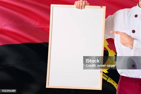 앙골라 국기 배경에 빈 화이트 보드 메뉴를 들고 앙골라 요리사 텍스트에 대 한 균일 한 포인팅 공간을 착용 요리 고급 요리에 대한 스톡 사진 및 기타 이미지 Istock