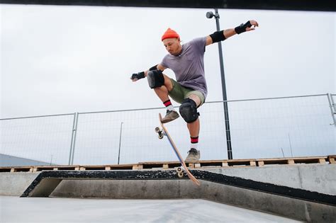 Premium Photo Agile Mature Skater In A Watch Cap Doing Tricks With A Skateboard On A Ramp In A