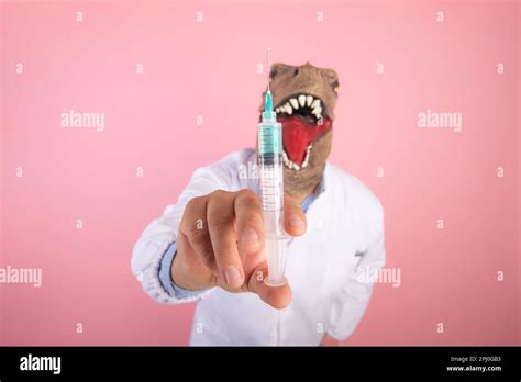 Funny And Surreal Concept Of Doctor Holding A Syringe Close Up On An Isolated Pink Background