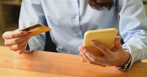 한 여성이 신용카드와 스마트폰을 손에 들고 거실에 앉아 있는 모습이 자른다 사진 Unsplash의 가로 이미지