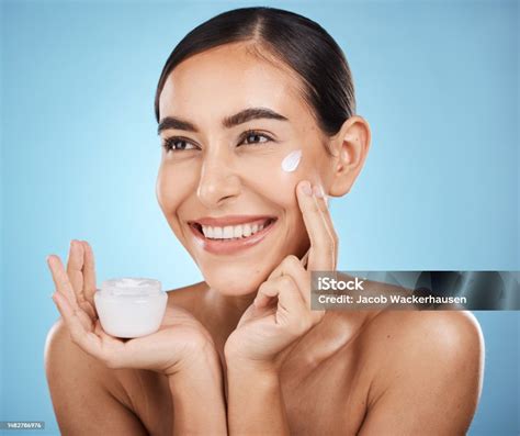 얼굴 크림 그리고 스튜디오에 있는 여자의 스킨케어 제품은 파란색 배경에 고립되어 있다 화장품 미학 행복한 여성 모델은 아름다움과 웰빙을 위해 로션 크림 또는 모이스처라이저에