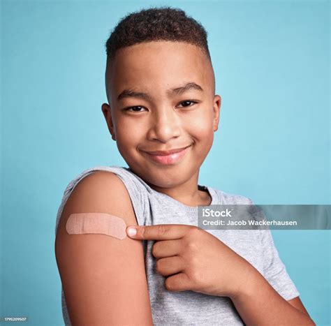 어린이 흑인 반창고 및 백신을 가진 행복한 아이 파란색 스튜디오 배경에서 미소 또는 기쁨으로 휴식을 취하십시오 초상화 소년 및 팔 타박상이 있는 접착 붕대 자신감과 건강을