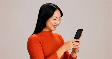 아시아 여성 온라인 데이트 연락처 및 웹 채팅을 배경으로 스튜디오에서 미소를 지으며 전화 및 문자 메시지를 보냅니다 모바일 앱이