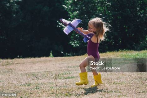 수영복을 입은 어린 소녀가 즐겁게 웃으며 여름에 비행기를 하늘로 발사합니다 한 아이가 비행기로 공터를 통과합니다 행복한 어린 시절 진실한 감정 아이들을위한 활동적인 게임 2