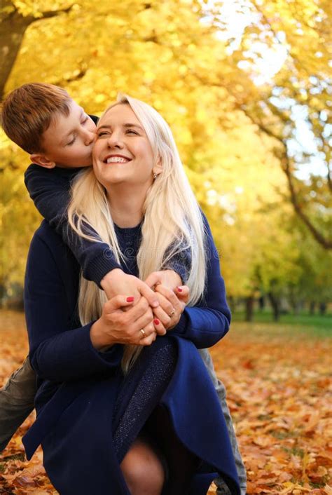 Mother And Son In Autumn Park Son Kisses Mother Mother Smiles Stock
