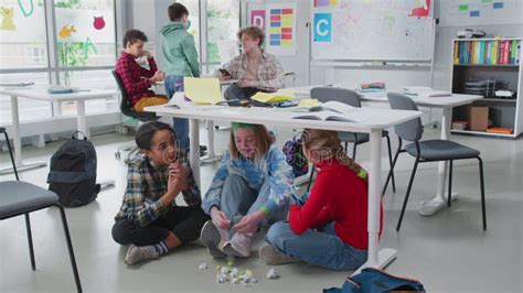 Diverse Teen Girlfriends Sit Under Desk In Class And Gossip Stock Video Video Of Campus