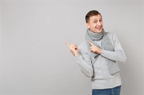 회색 스웨터 스카프 가리키는 인덱스 손가락 옆으로 스튜디오에 회색 배경에 고립에서 젊은 남자를 놀 랐 다 건강 패션 라이프 스타일 사람들이 진심으 감정 추운 계절 개념 복사