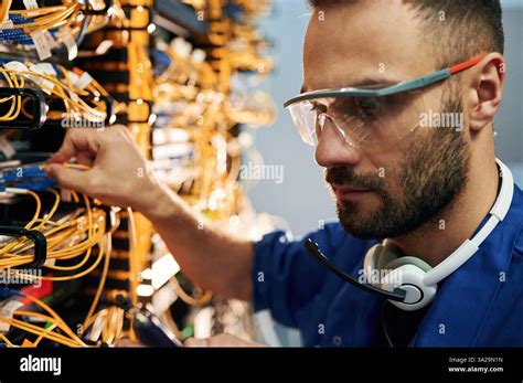 Modern Technology Routing Young Man Is Working With Internet Equipment And Wires In Server Room