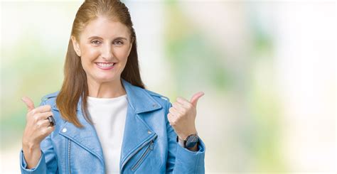 아름 다운 중 년 여 인 착용 패션 가죽 자 켓 손으로 긍정적인 제스처를 하 고 격리 된 배경 성공 기호에 엄지 웃 고 행복 쾌활 한 식 우승자 제스처와 카메라를 보면