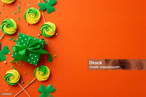 성 패트릭의 날 개념 활 머랭 막대 사탕 뿌리고 복사 공간이 있는 격리된 생생한 주황색 배경에 트레포일이 있는 작은 선물 상자의 상위 뷰 사진 3월에 대한 스톡 사진 및