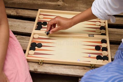 People Playing Backgammon On A Wooden Board Outdoors Enjoying A Friendly Game Stock Image