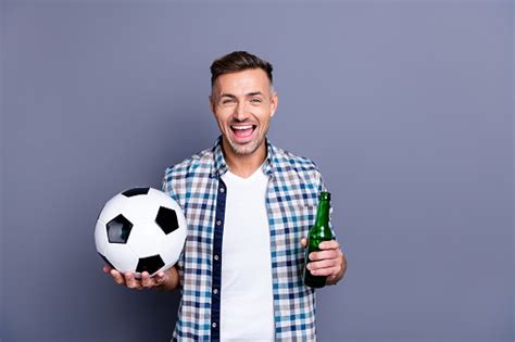 그의 초상화 그의 좋은 매력적인 쾌활 한 쾌활 한 기쁜 수염 남자 를 입고 체크 셔츠를 입고 손 축구 공 빛 맥주 회색 파란색 배경 위에 고립 Championship에 대한