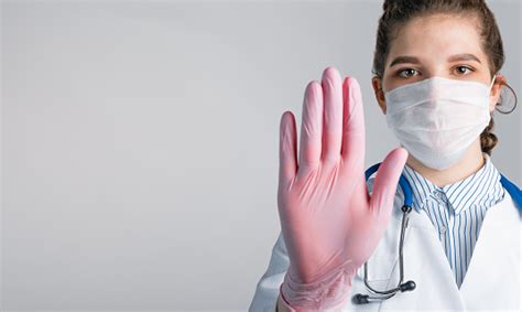 흰색 코트와 분홍색 멸균 장갑을 입은 젊은 아름다운 여성 의사가 정지 제스처를 보여줍니다 바이러스 질환 없음 개념에 대한 스톡