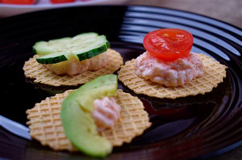 검은 접시에 간식이 있습니다 치즈 스프레드가 있는 크래커 샌드위치 얇게 썬 오이 토마토 아보카도치즈 크래커 건강한 간식 곡초류에