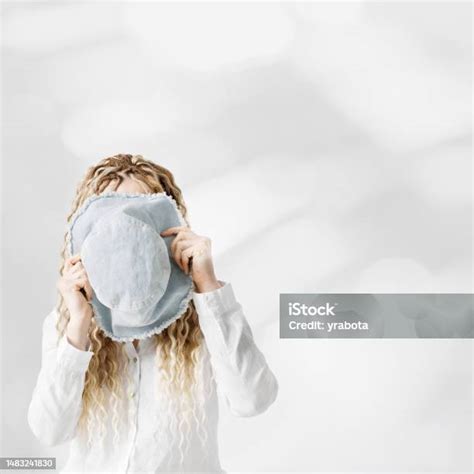 창의적인 여름 비주얼 미적 휴가 휴가 개념 얼굴 앞에 태양 모자를 들고 있는 여성 얼굴 트렌드 개념이 없다 푸른 파나마 뒤에 숨어있는 긴 머리를 가진 세련된 여성 여름