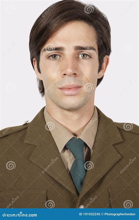 Портрет молодого человека в военной форме против серого цвета фона Стоковое Изображение