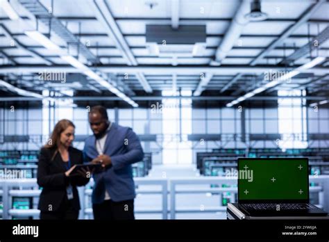 focus on isolated screen laptop device used by coworkers in data center blurry background close